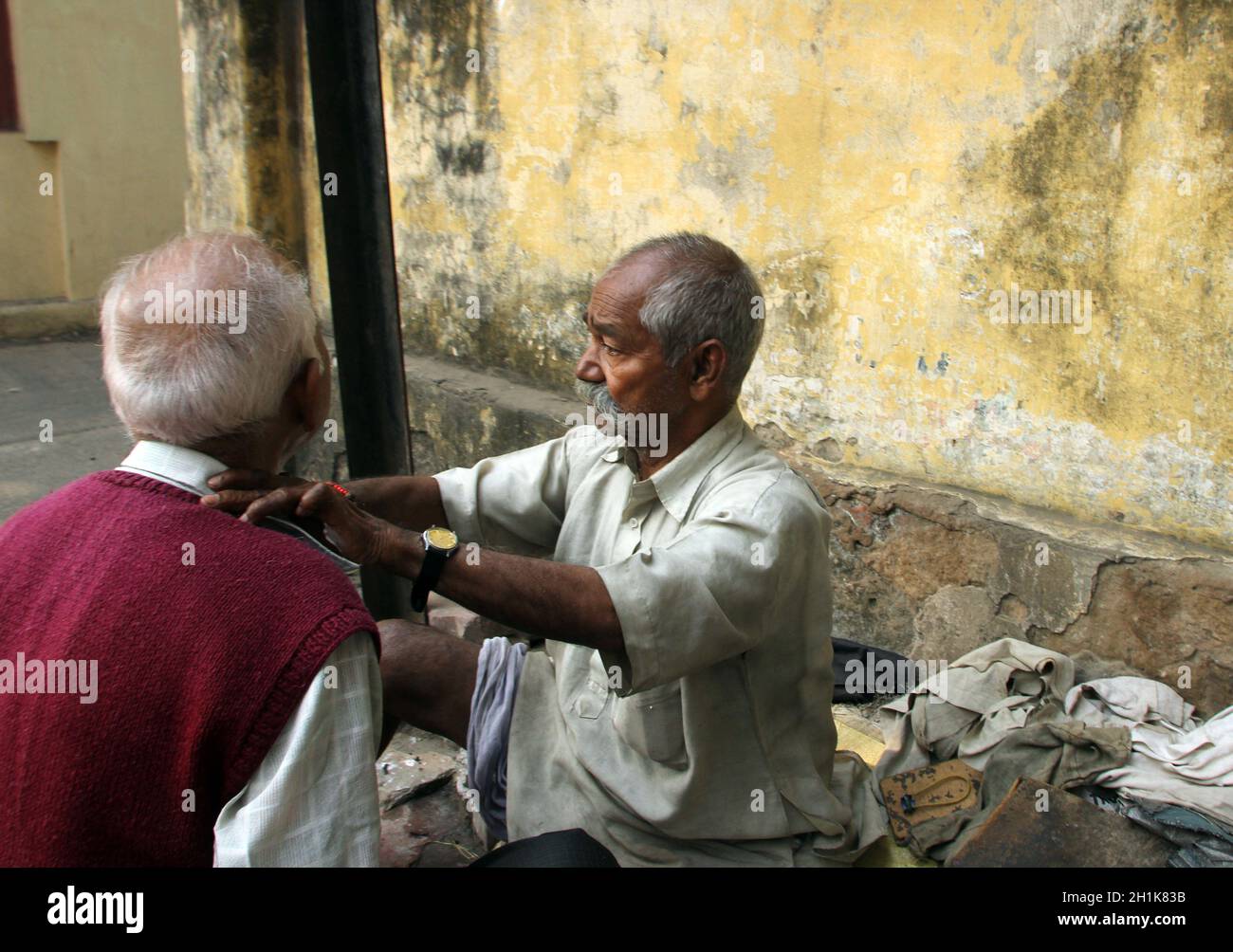 Street barber shaving a man using an open razor blade on a street in ...