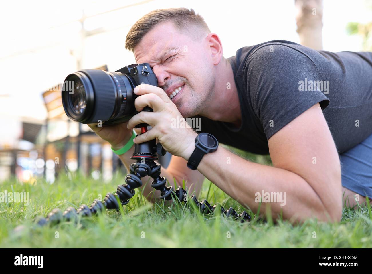 Male photographer makes photos on tripod while lying on ground Stock ...