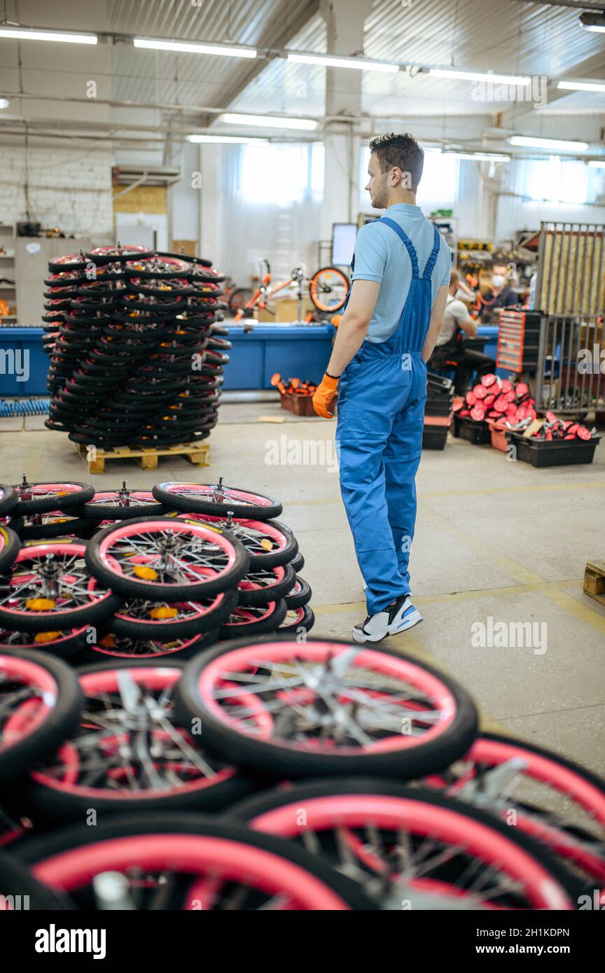 Bicycle factory, worker at the stack of bike wheels. Male mechanic in ...