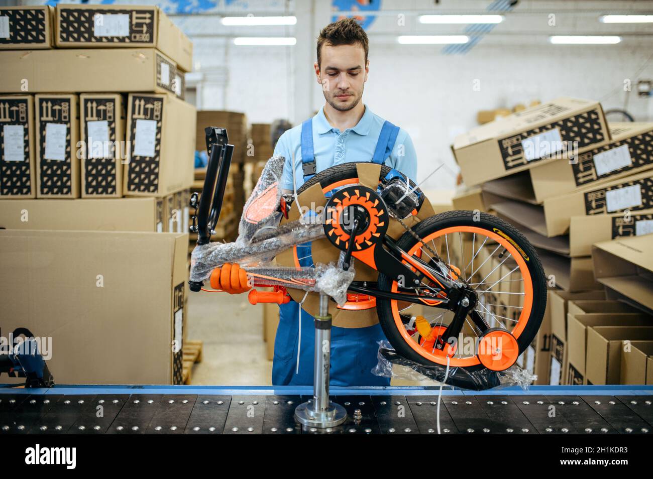 Bicycle factory, worker packs teen bike. Male mechanic in uniform ...