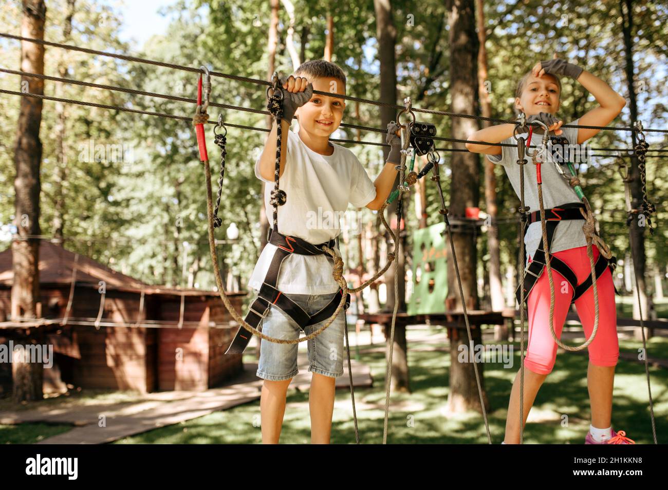 Little girl and boy climbs in rope park. Children climbing on ...