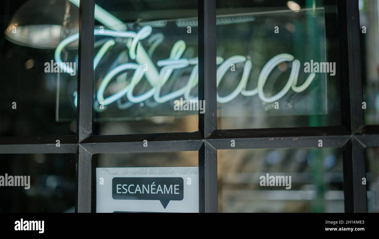 Picture of a blue Tattoo light sign on a window from barber shop and ...