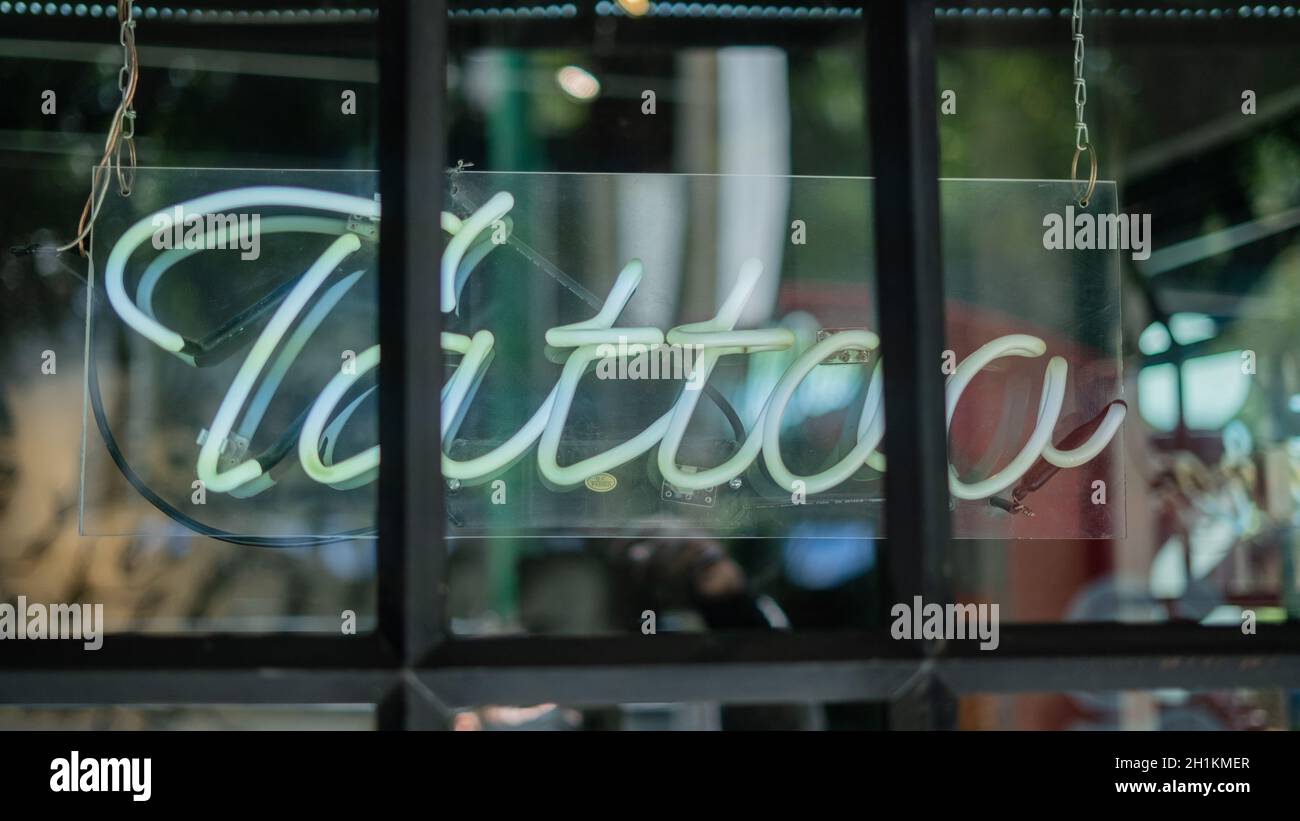 Picture of a blue Tattoo light sign on a window from barber shop and ...
