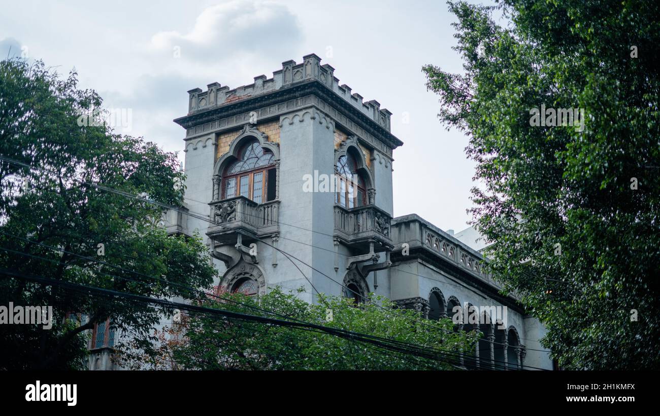 Picture of a building with medieval style architecture behind a tree ...