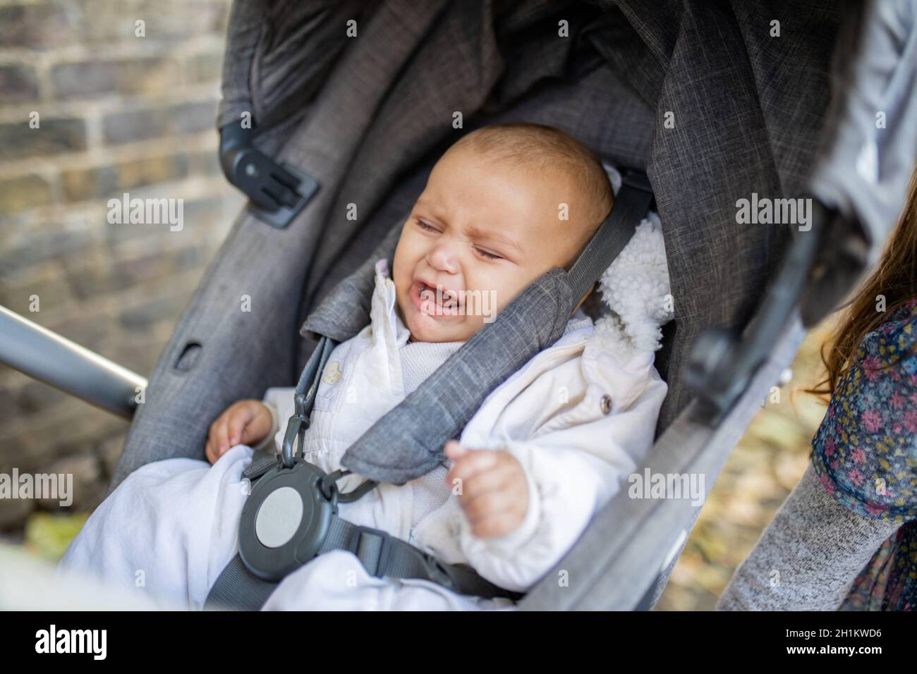 Picture of a distressed baby in gray clothing crying with eyes closed ...