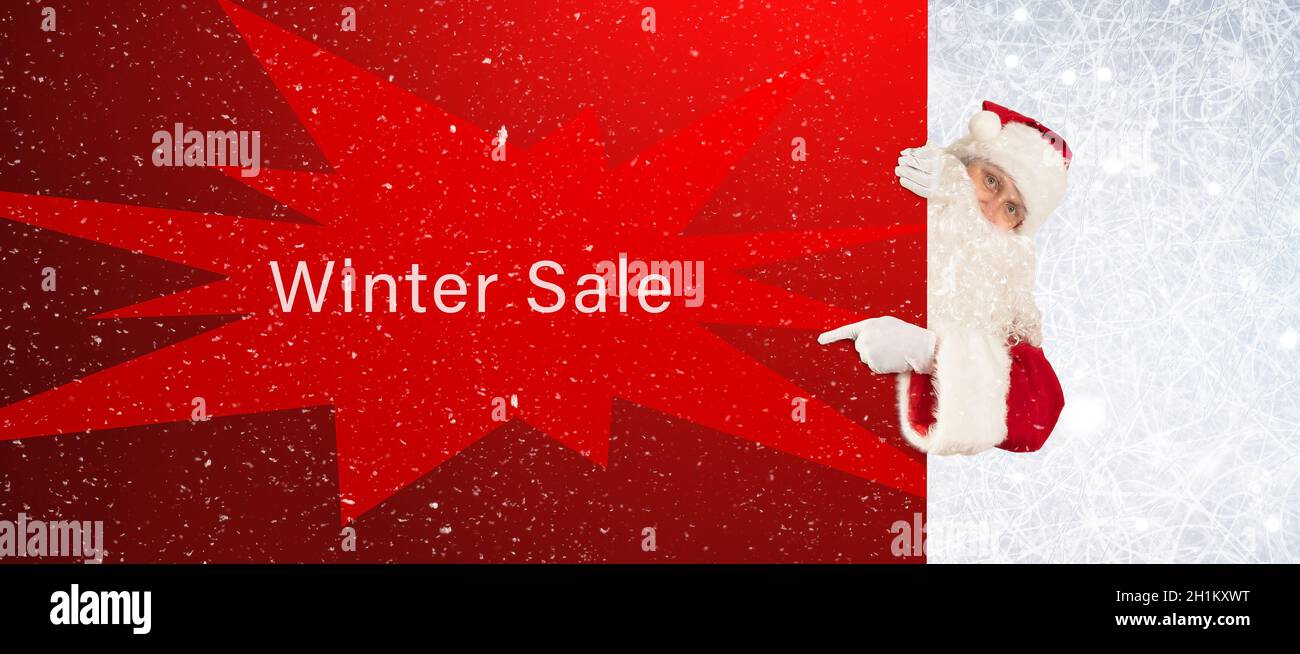 Santa claus points with his finger at a board with the text winter sale ...