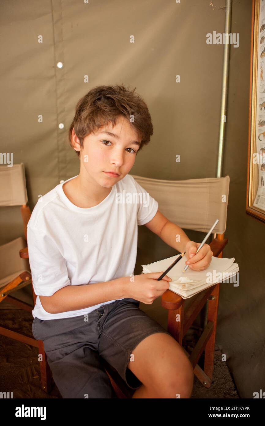 Tween boy journaling at safari camp Stock Photo - Alamy