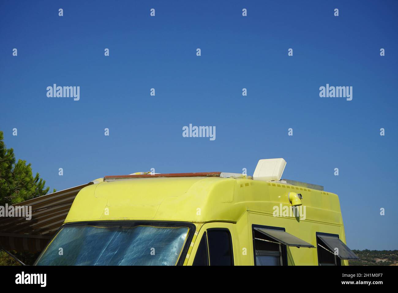 Close up of the up part of a yellow caravan under a blue sky on a sunny ...