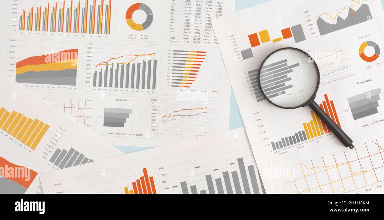 Business graphs, charts and magnifying glass on table. Financial ...