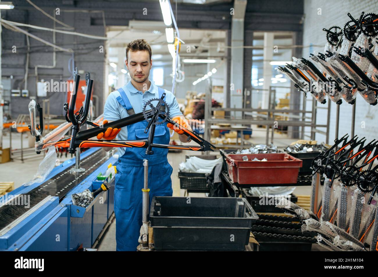 Bicycle factory, worker holds black teen bike frame. Male mechanic in ...