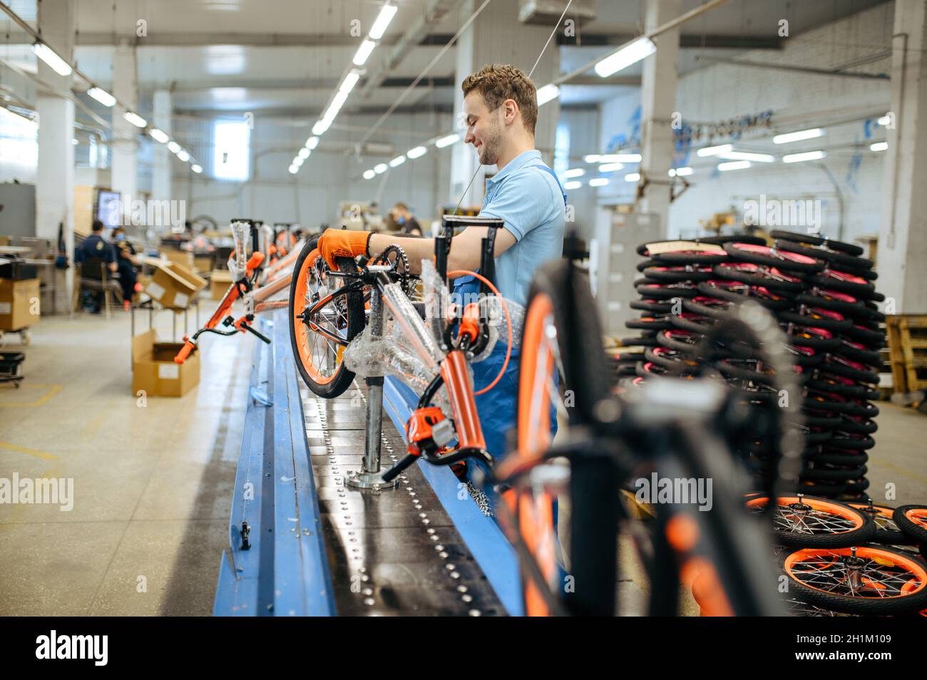 Bicycle factory, worker at assembly line, chain installation. Male ...
