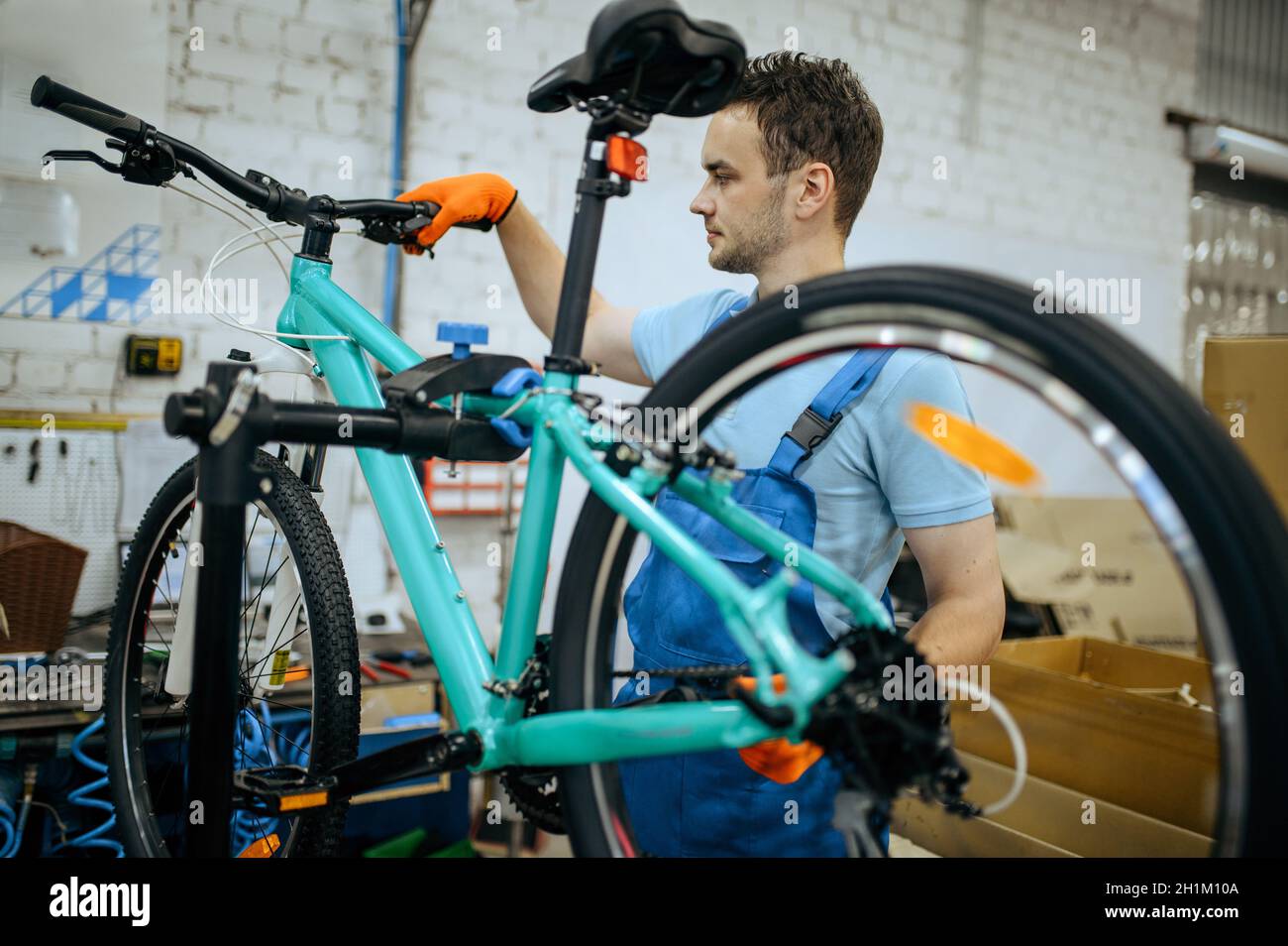 Bicycle factory, worker holds mountain bike. Male mechanic in uniform ...