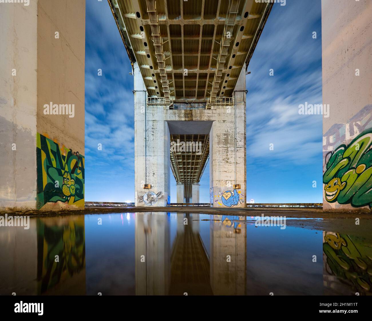 Bottom view of bridge with columns with graffiti. Night view with ...