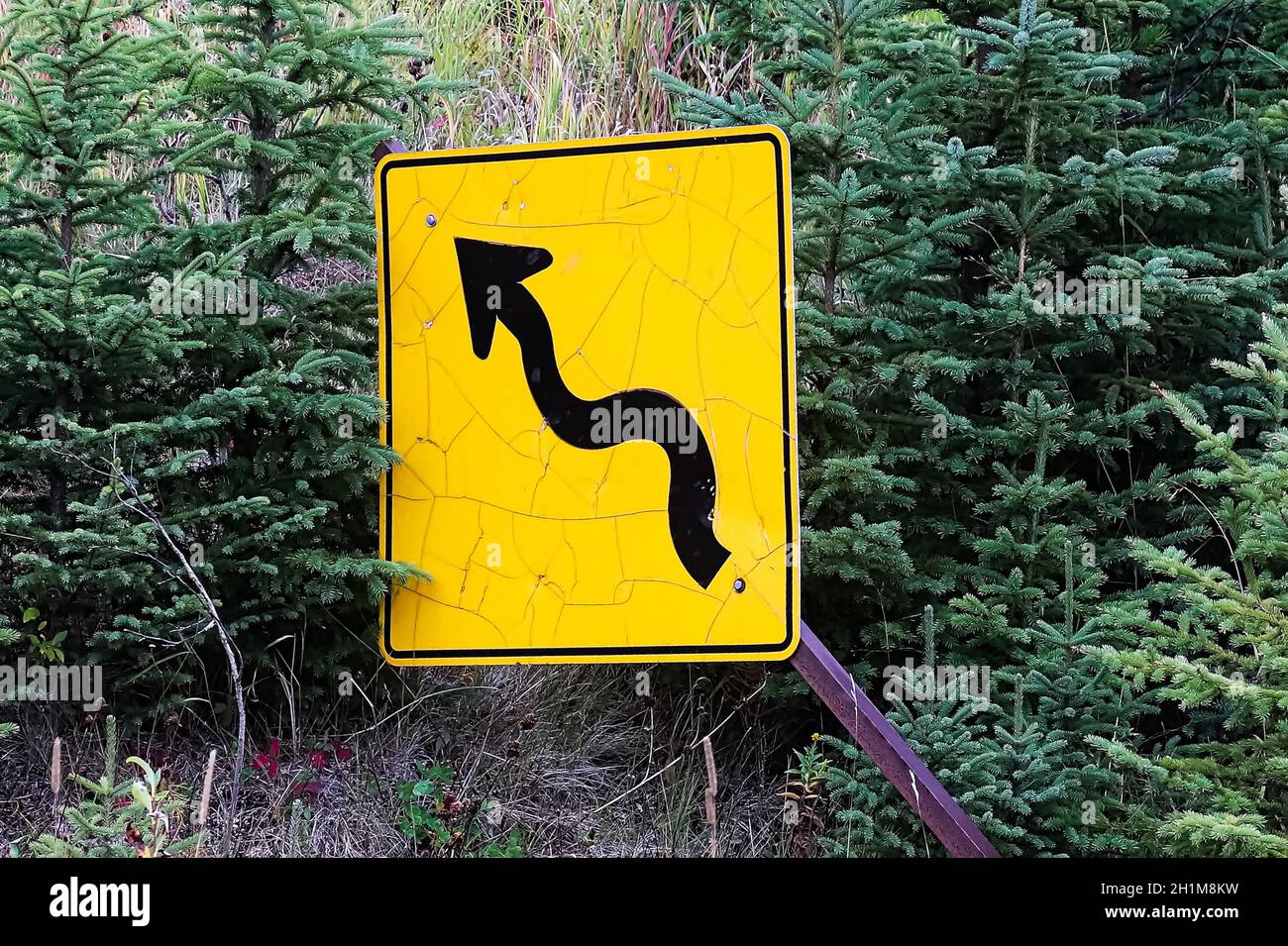 A windy road ahead sign that has been tipped over Stock Photo - Alamy