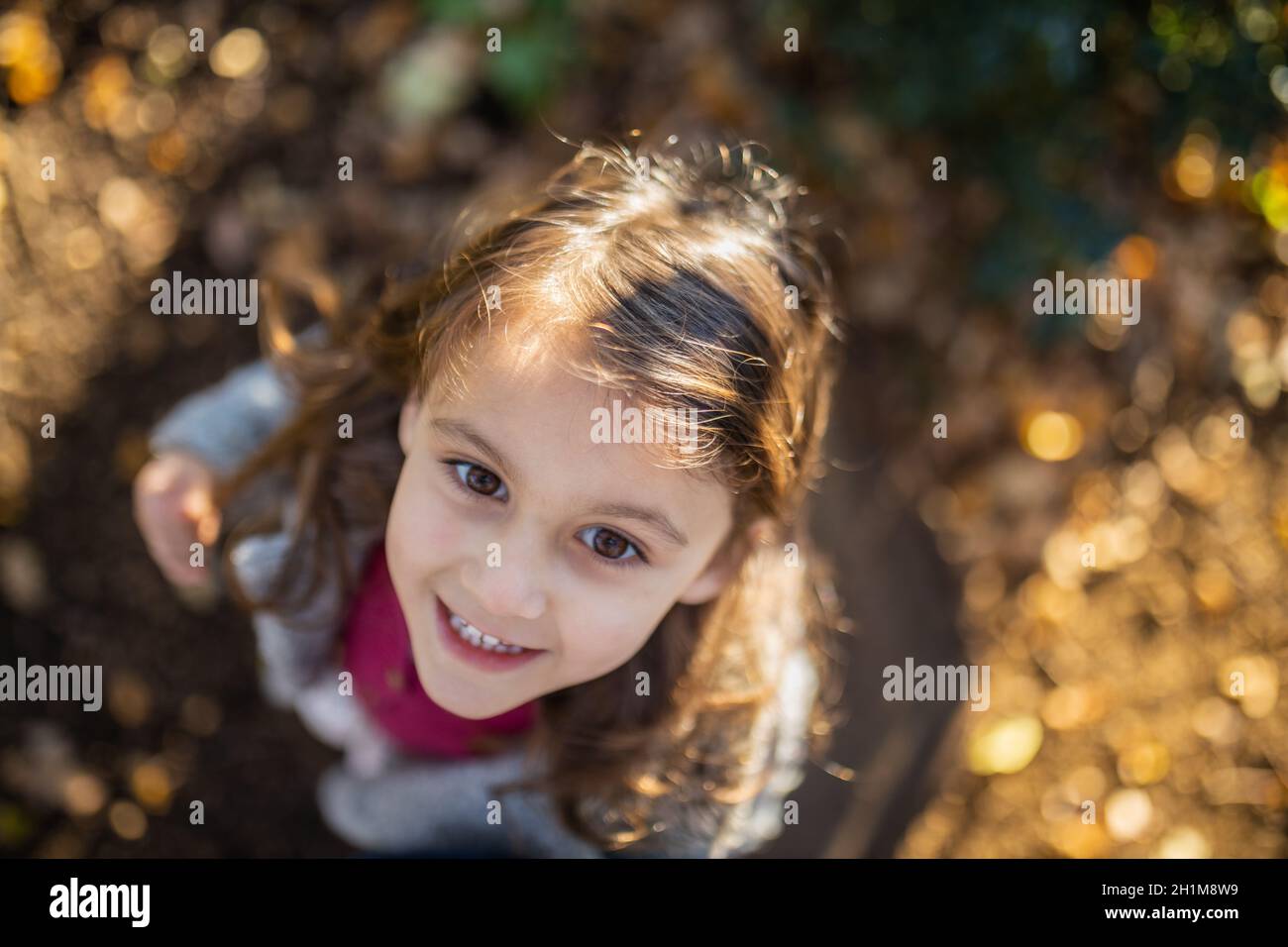 Happy little girl from above looking up at the camera and smiling ...