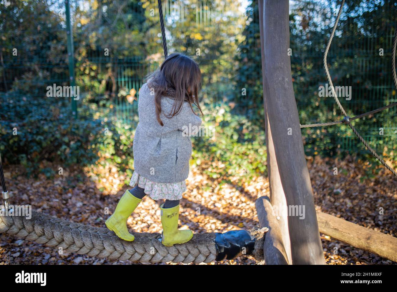 Little girl playfully crossing a small playground bridge in a park ...
