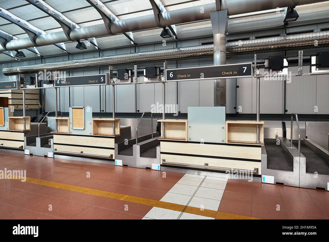 Check in counters and luggage conveyor belts at an empty airport terminal building unused during ...