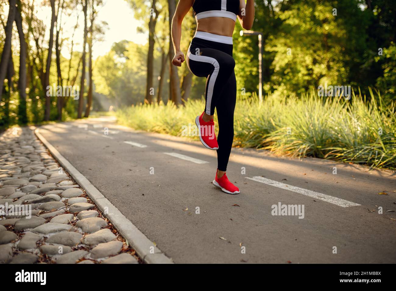 Morning training in park, woman running on walkway. Female runner goes ...