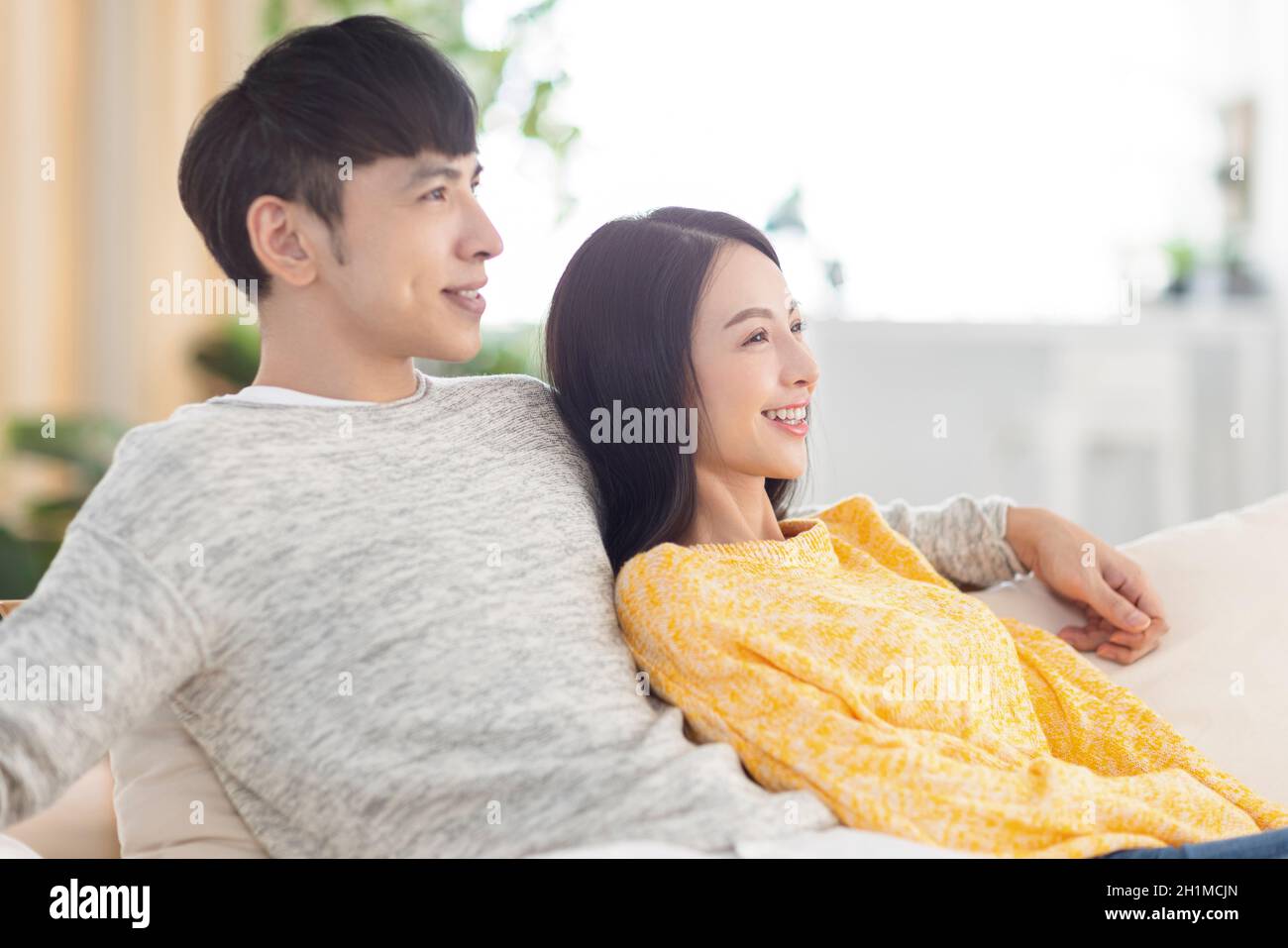 Young happy couple sitting together in the living room Stock Photo - Alamy