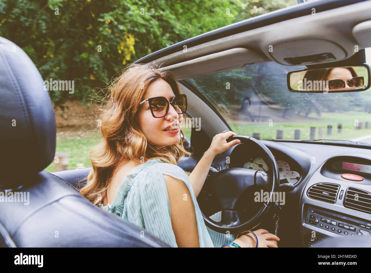 Pretty young woman driving convertible car. Happy girl drive on summer ...