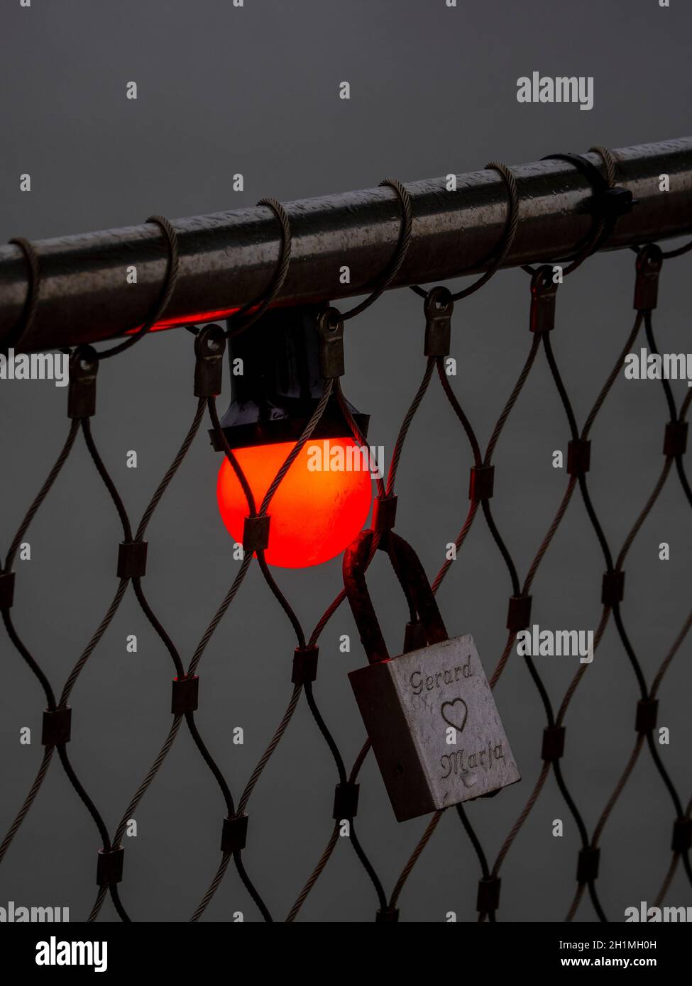 Love Lock Under a Red Light Bulb Attached to a Bridge Railing ...
