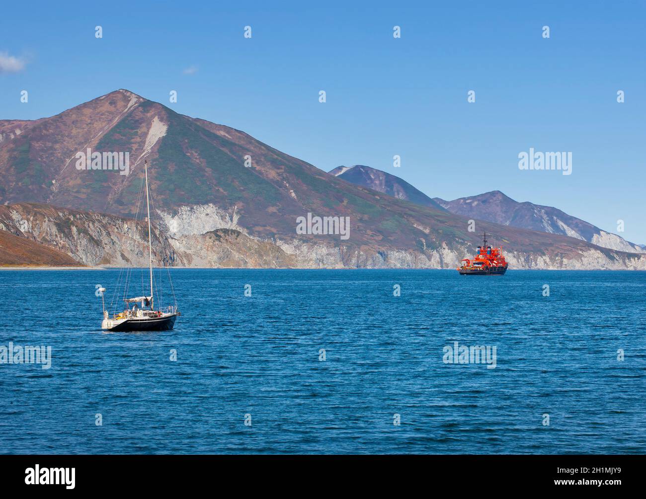 The Kamchatka Peninsula Pacific Coast Sailing Yacht And Red Ship In