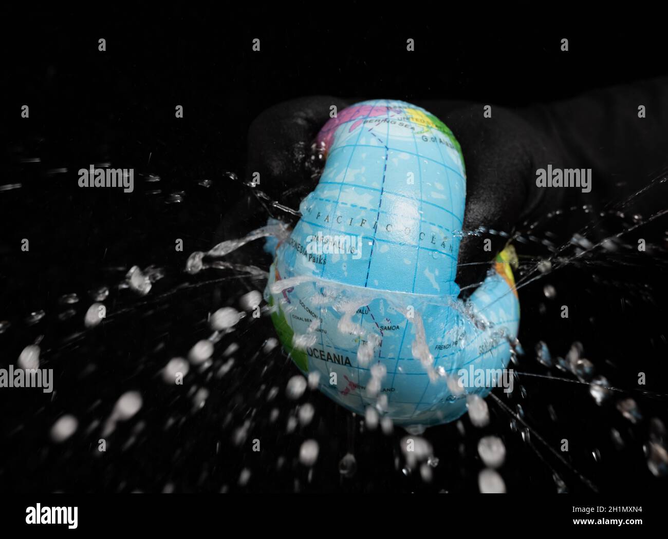 squeezing a globe and water flying out concept of human overusing the ...