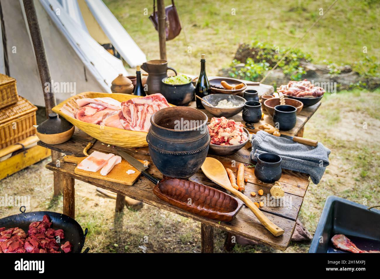 Chopped raw meat, homemade food and pottery on the table at historical ...
