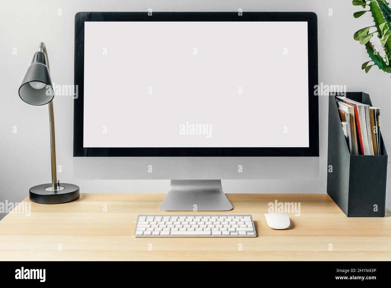 Computer monitor with mockup white screen on office table with supplies ...
