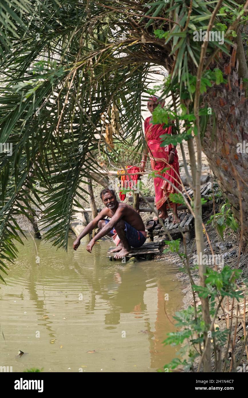 Man preparing to bath in a small pond in front of his house in ...