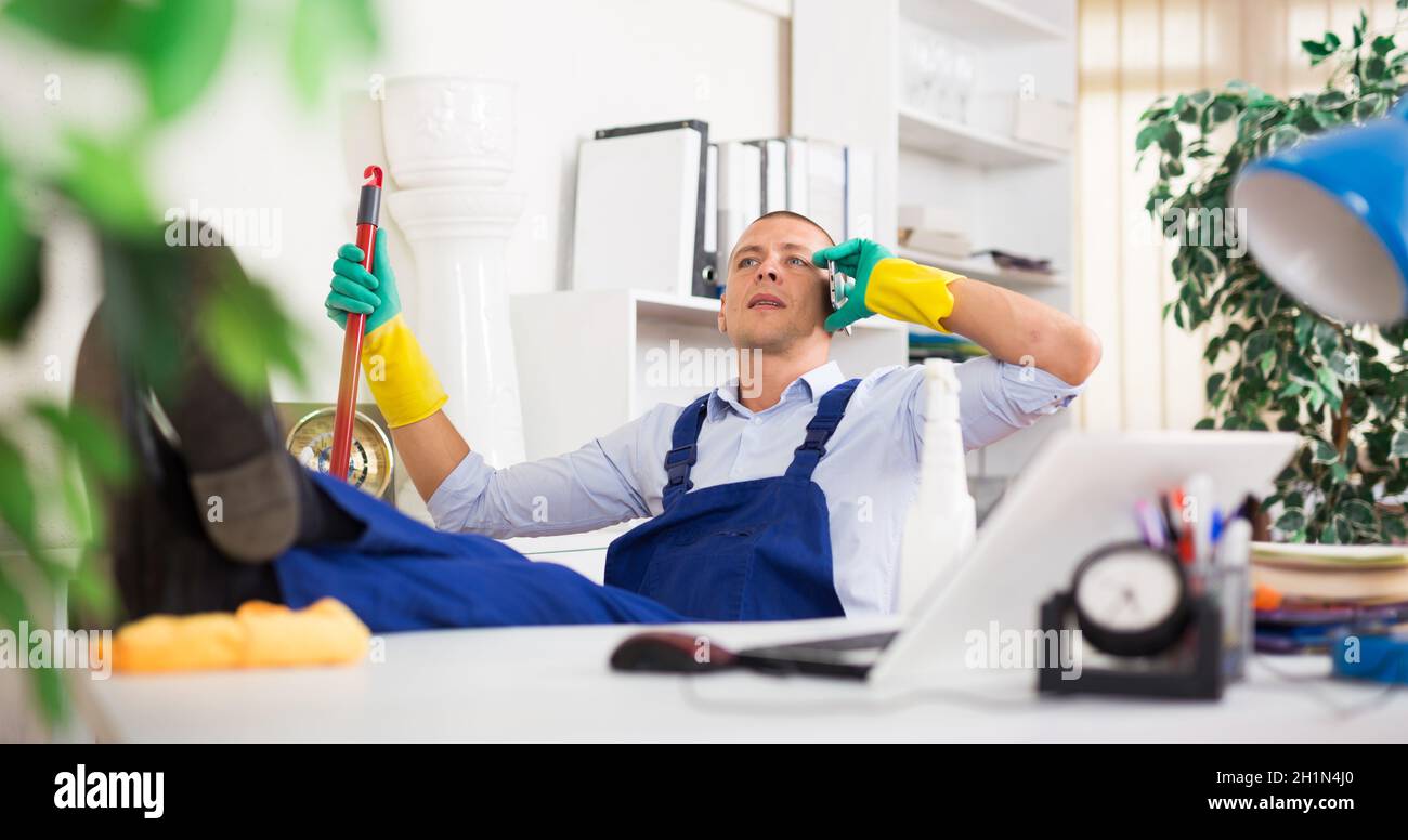Relaxed worker of office cleaning service talking on phone during break ...