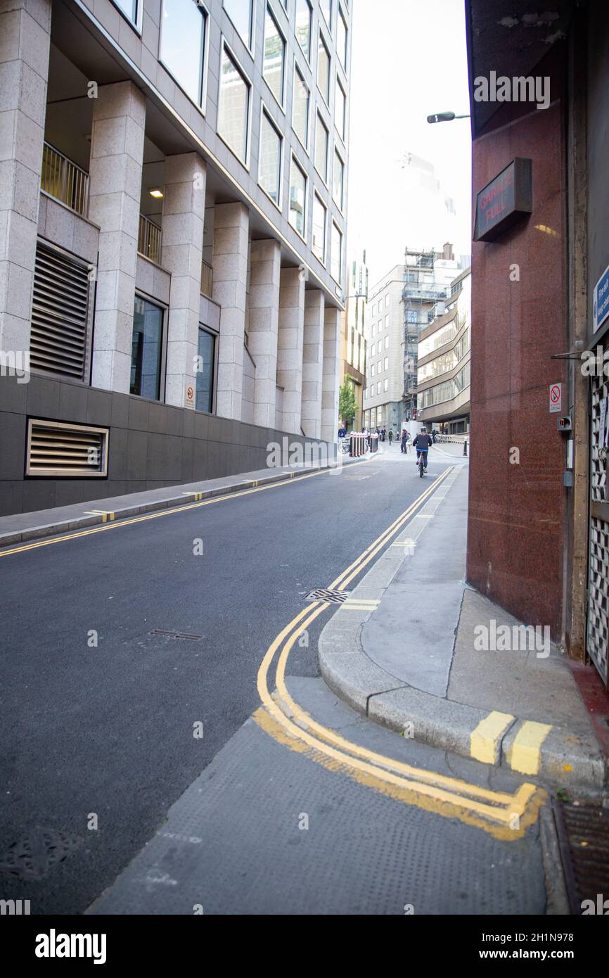 Modern big buildings in British narrow street with pedestrians passing ...