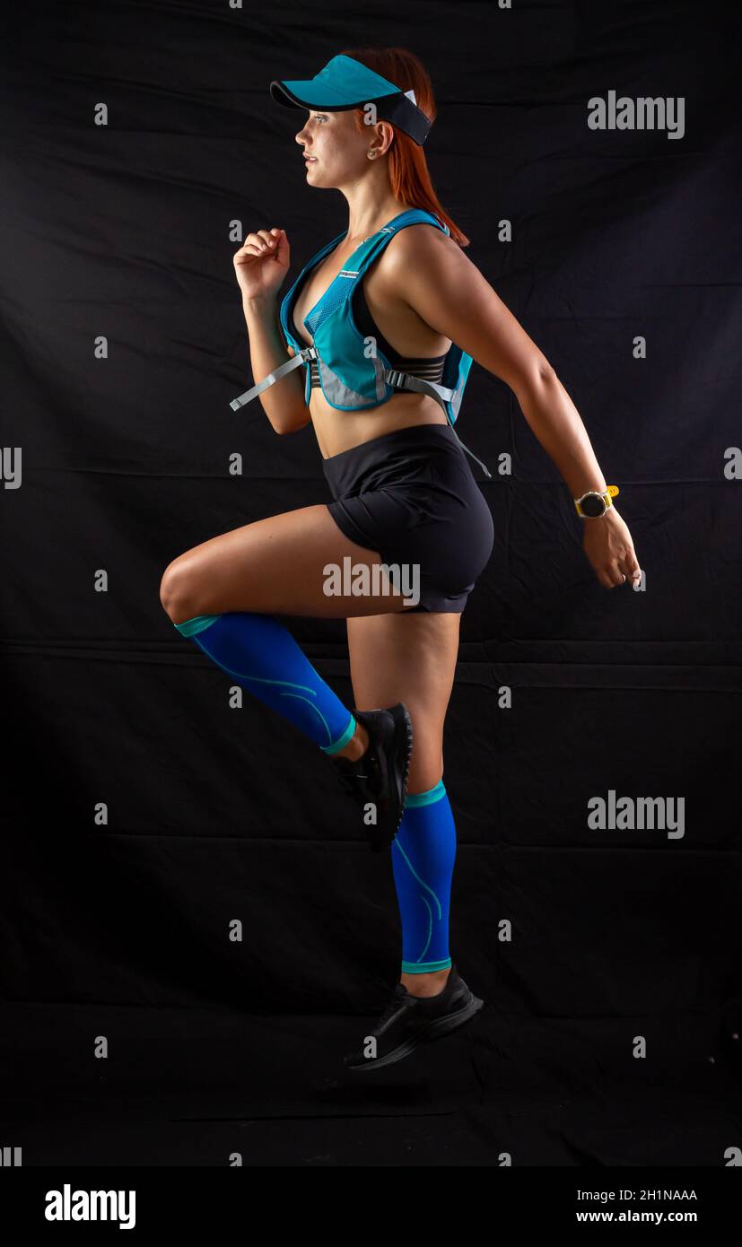 girl in blue jogging uniform runs in the studio on a black background ...