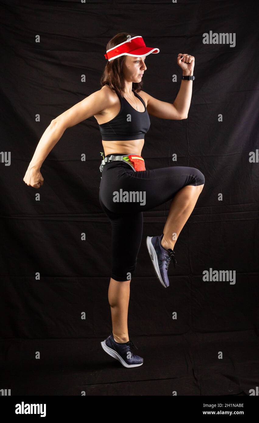girl in red jogging uniform runs in the studio on a black background ...