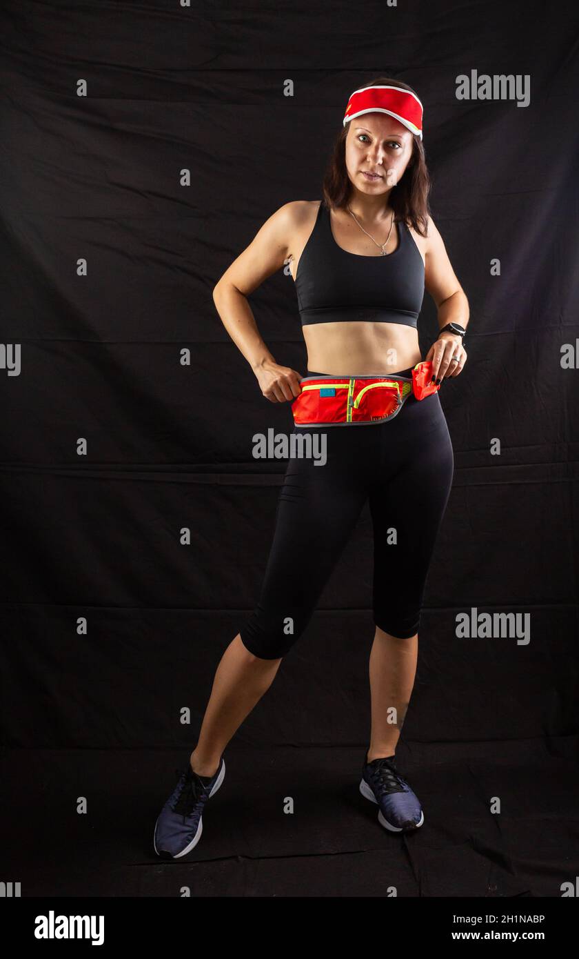 Beautiful redhead girl in jogging uniform posing in studio on black ...