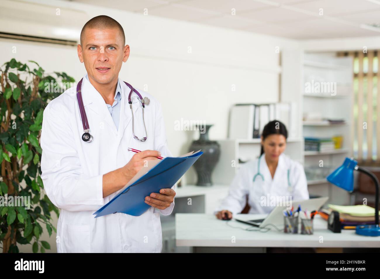 Doctor standing in modern office with document Stock Photo - Alamy