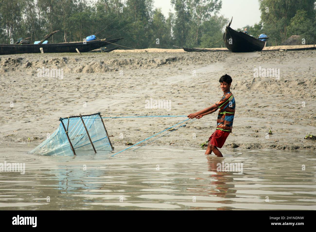 Fisherman uses fishing net in a traditional way for fishing in a river ...