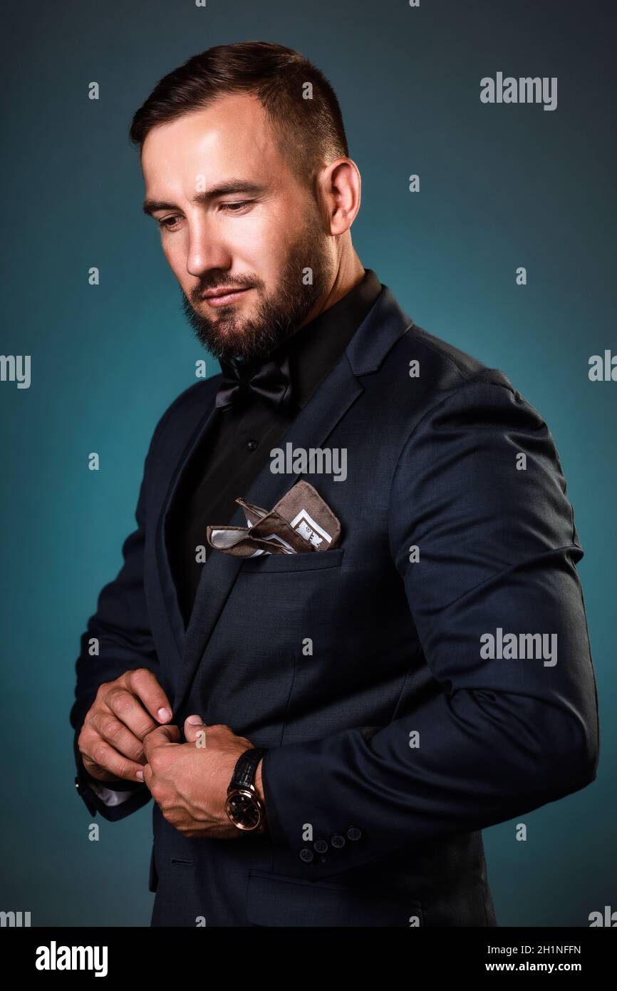 An elegant business man fastens a classic jacket. Studio portrait of a ...
