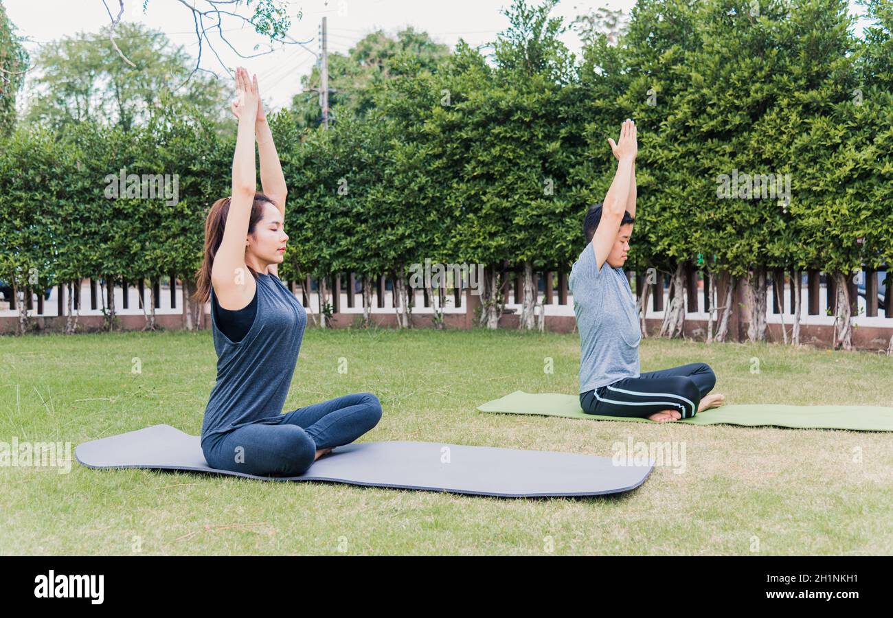 Asian man and woman practicing doing yoga outdoors in meditate pose ...