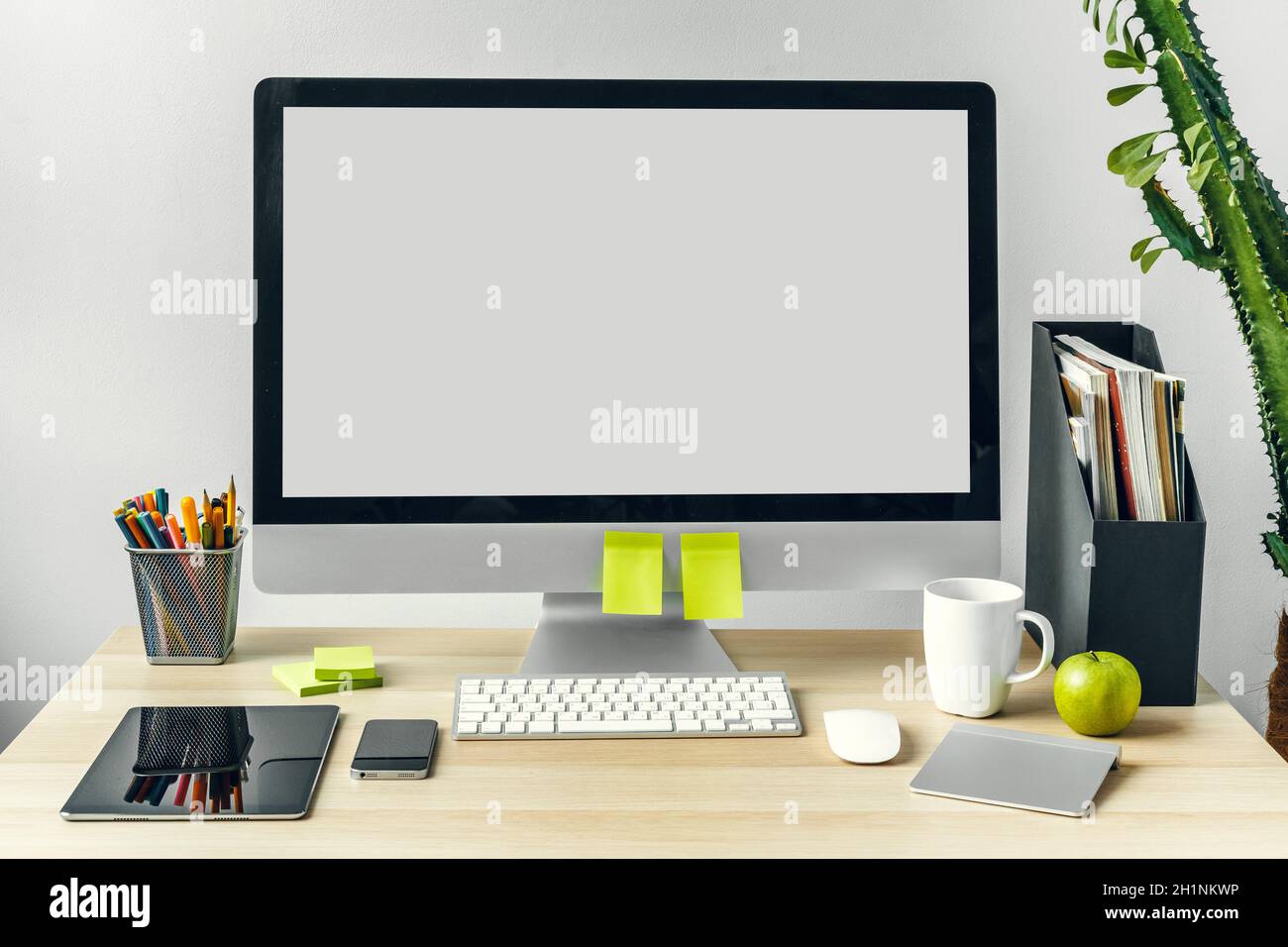 Computer monitor with mockup white screen on office table with supplies ...
