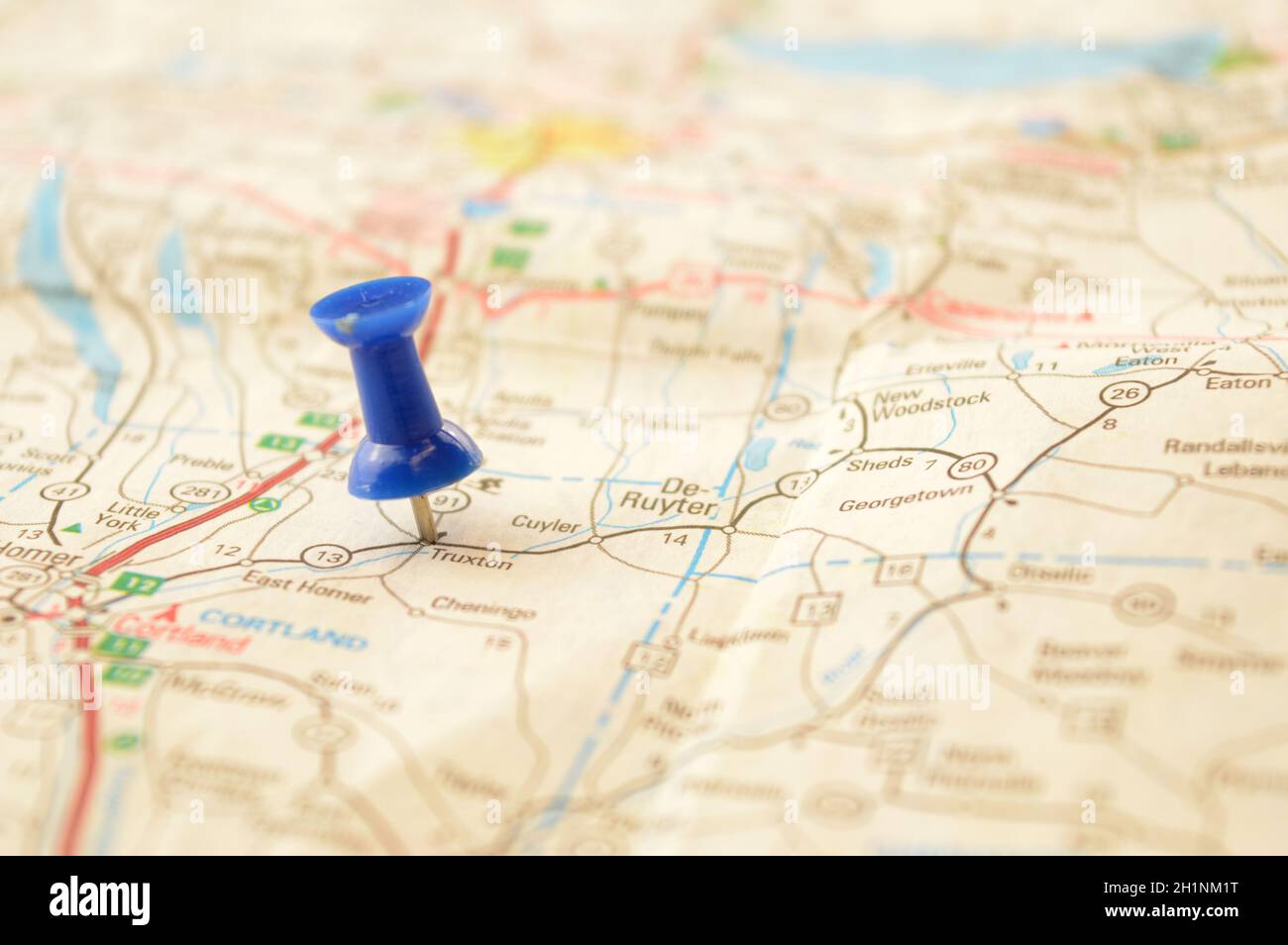 A blue pin pressed into a map detailing a point of interest Stock Photo ...