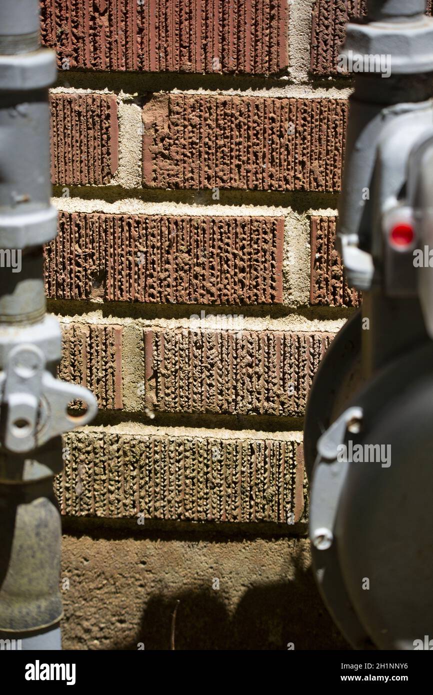 Dingy red brick wall between a water meter and water meter pipe Stock ...