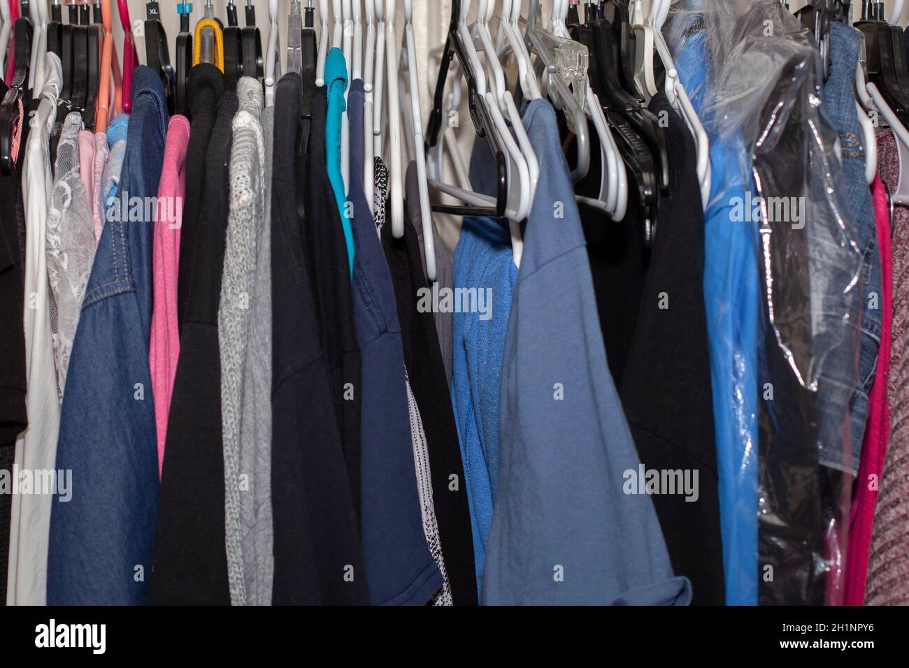 Open closet full of pink, blue, yellow and red clothes Stock Photo - Alamy