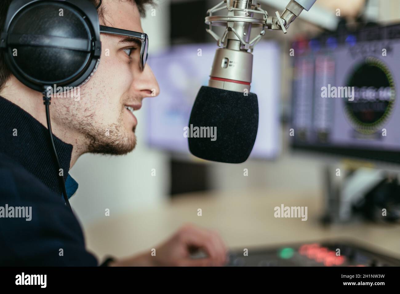 Young man in the broadcasting studio, radio, talking into the ...