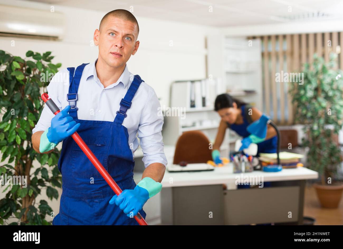 Male worker wiping office floor with mop Stock Photo - Alamy