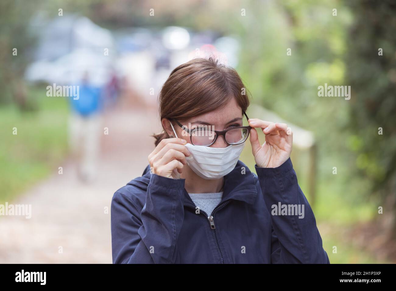 Young woman outdoors wearing a face mask and glasses, tarnished glasses ...