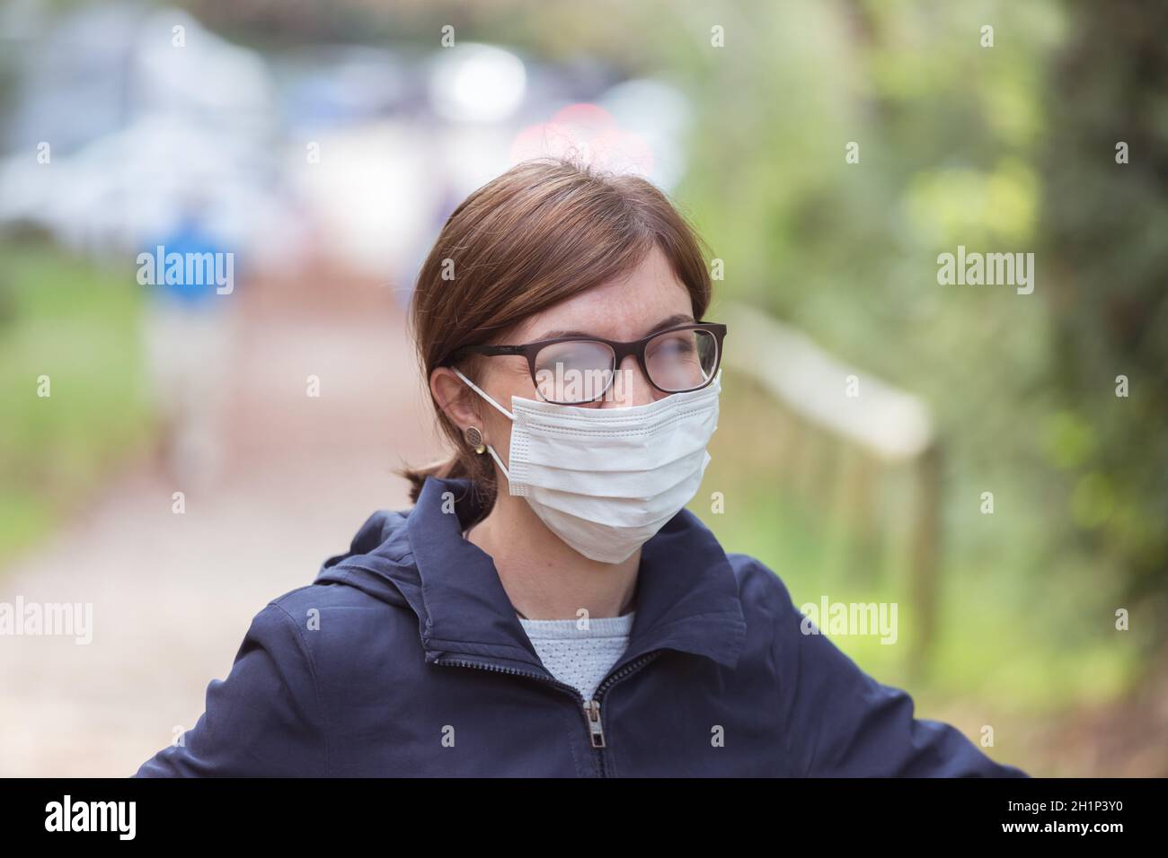 Young woman outdoors wearing a face mask and glasses, tarnished glasses ...