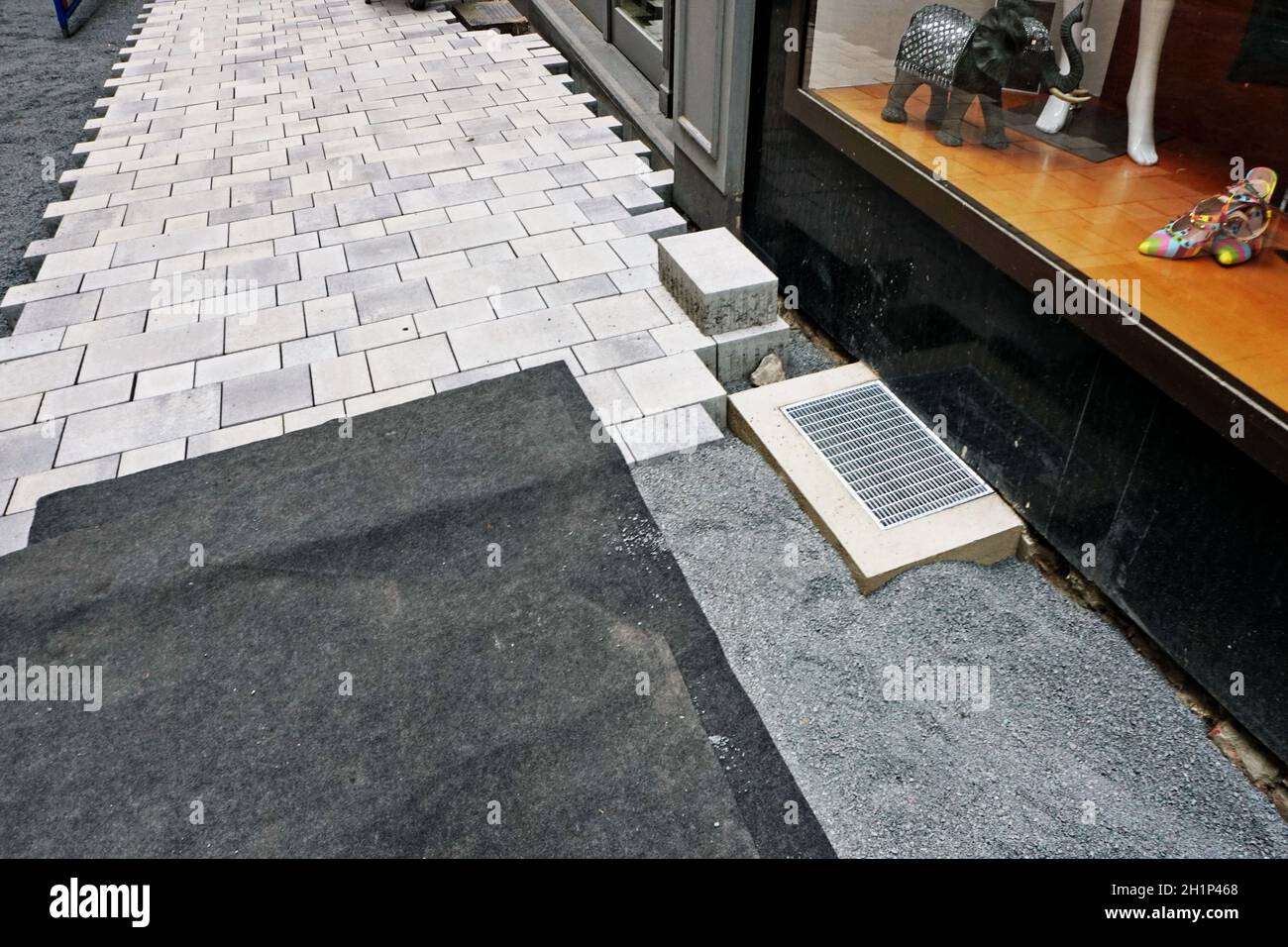 Laying paving slabs in the old town on a street with many storefronts ...