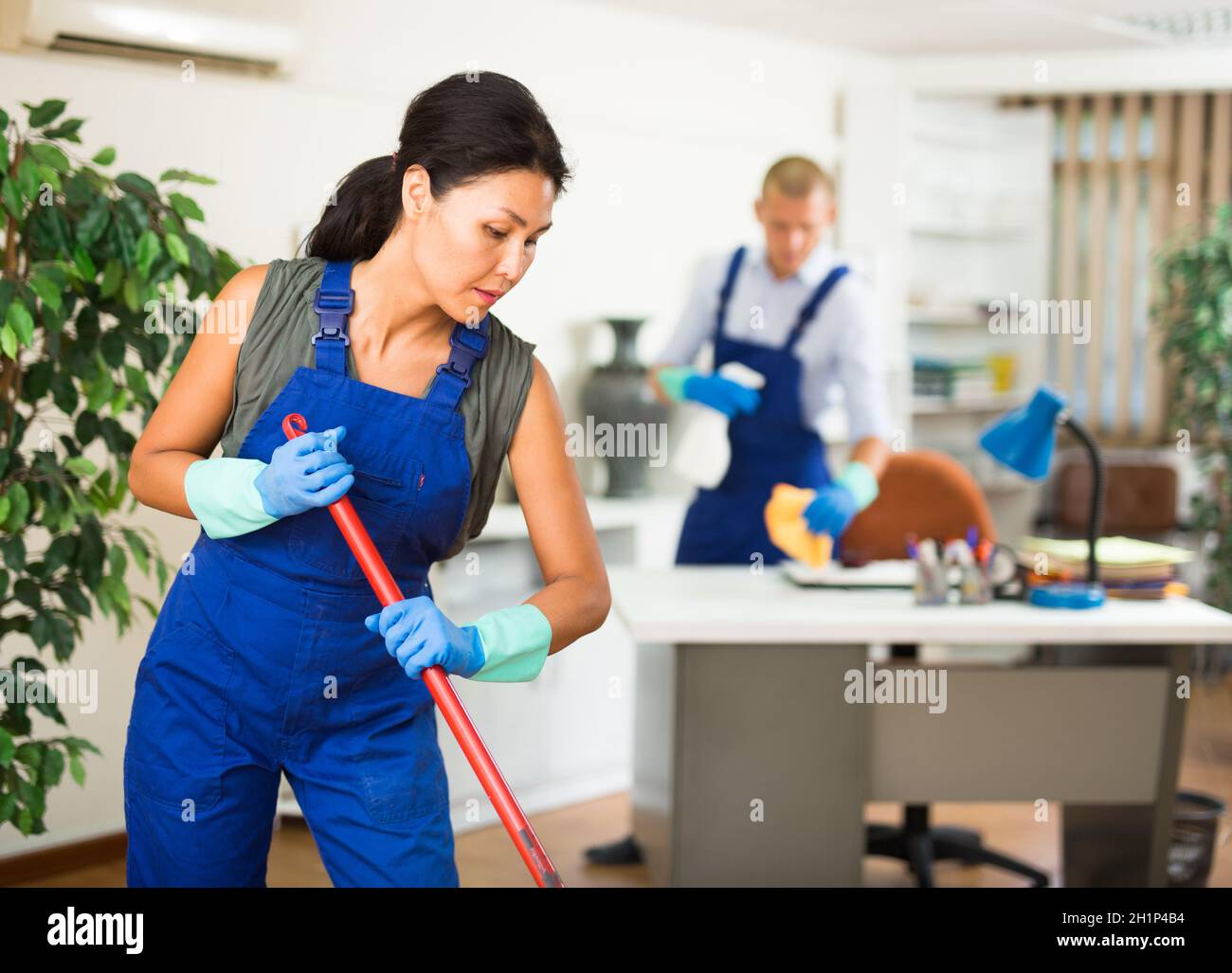 Professional female worker of office cleaning service mopping floors ...