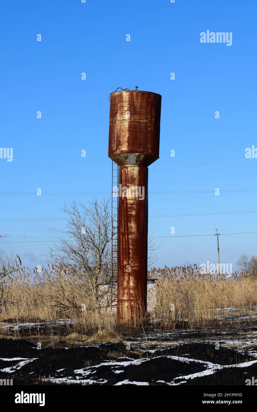 The old rusty water tower tilted. An old rustic communal communication ...